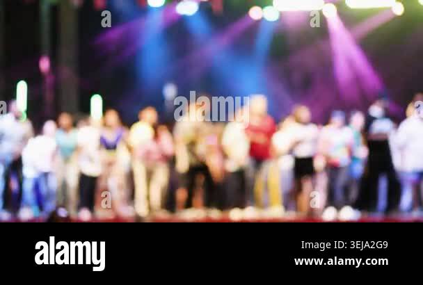 Blurred people dancing on concert stage with colorful lights at night ...