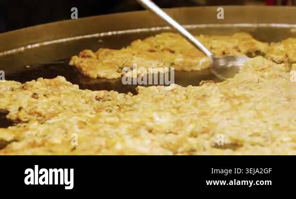 Oyster omelet cooking on a hot pan with metal spatulas. Delicious ...