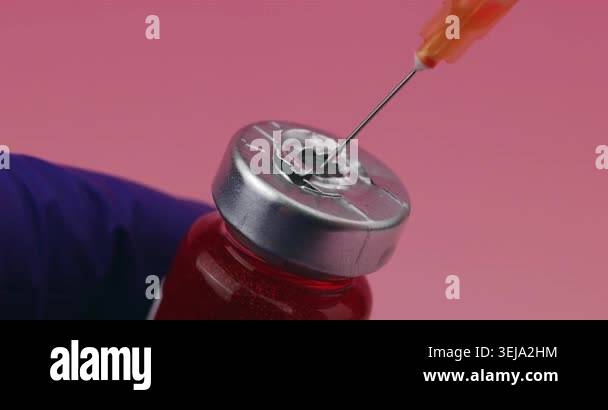 Detailed view of a syringe needle entering the rubber top of a medical ...