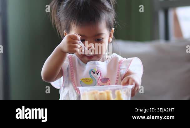 Happy child feeding snack independently, A little child feeds itself ...