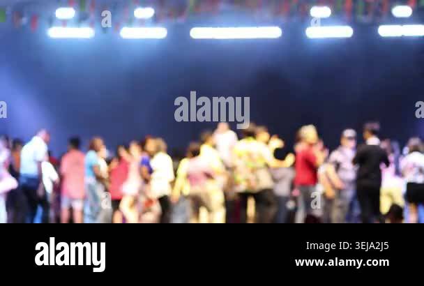 Blurred people dancing on concert stage with colorful lights at night ...