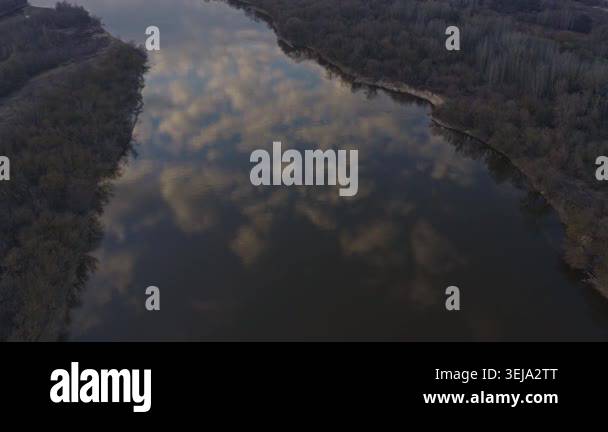 Aerial footage of a winding river bordered by dense forests under ...