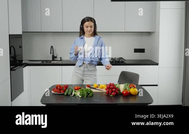 Happy young woman dancing while preparing salad Stock Video Footage - Alamy