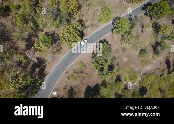 Aerial drone footage of a pickup truck driving on a rural road through ...