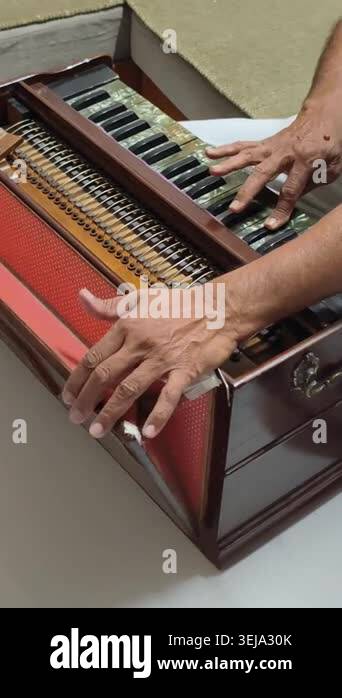 Close-up of hands playing a traditional harmonium, showcasing Indian ...