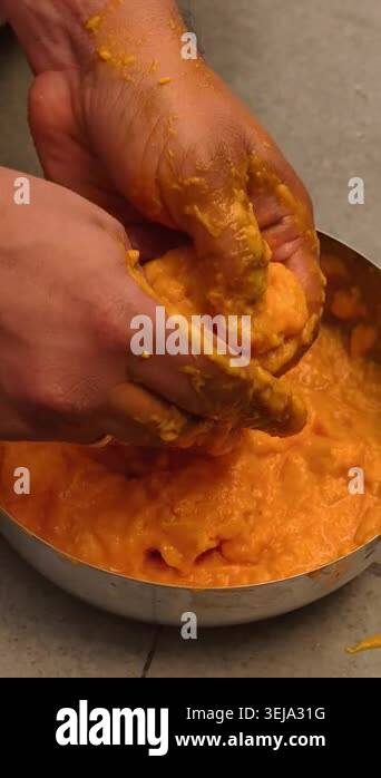 Close-up of hands extracting fresh mango pulp for traditional Aamras ...