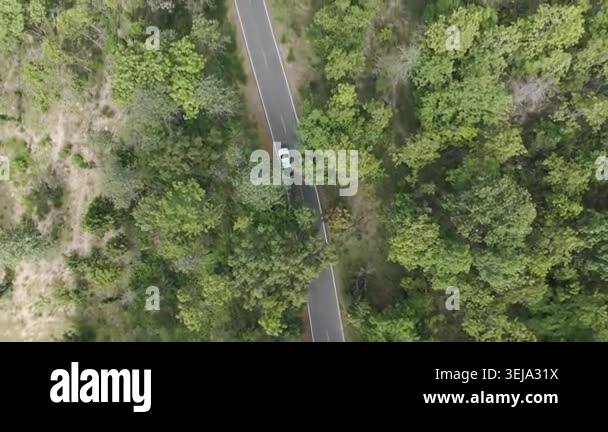 Aerial drone footage of a pickup truck driving on a rural road through ...