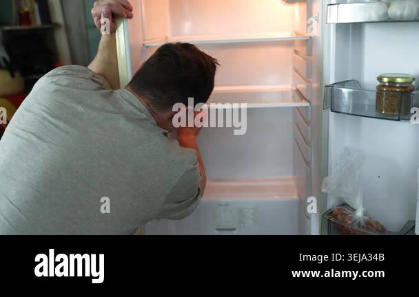 Young Caucasian man cleaning the inside of the fridge. Clean home ...