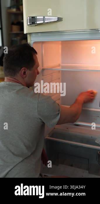 Young Caucasian man cleaning the inside of the fridge. Clean home ...