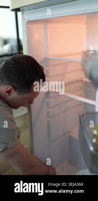 Young Caucasian man cleaning the inside of the fridge. Clean home ...