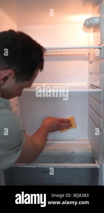 Young Caucasian man cleaning the inside of the fridge. Clean home ...