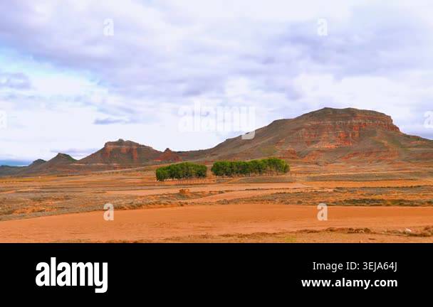wide angle view of arid desert landscape with rocky mountains and green ...