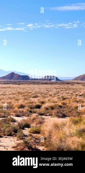 arid desert landscape with mountains under blue sky, dry grass prairie ...