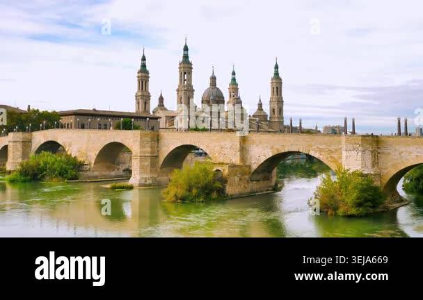 stone bridge crossing ebro river with basilica of our lady of the ...