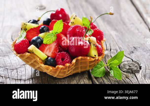 fresh berry fruit salad in waffle bowl on rustic wooden background ...