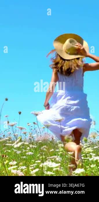 happy woman running in daisy field under blue sky, carefree summer ...