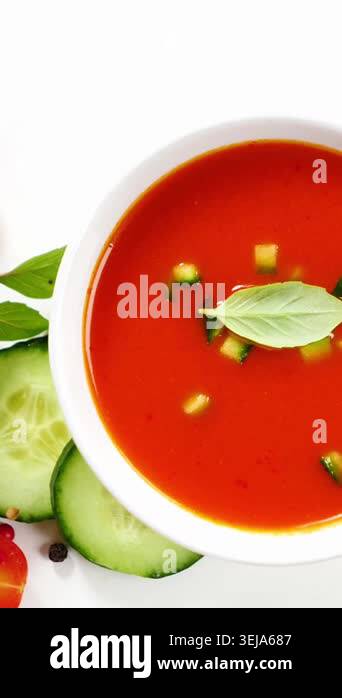 top view of fresh tomato soup or gazpacho in a white bowl garnished ...