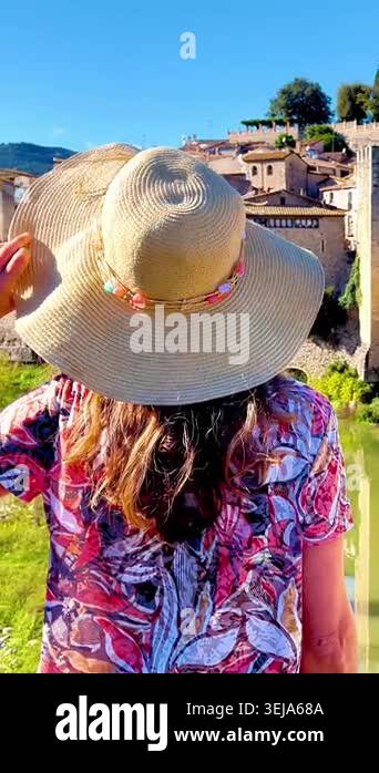 female tourist with straw hat looking at medieval village, woman ...