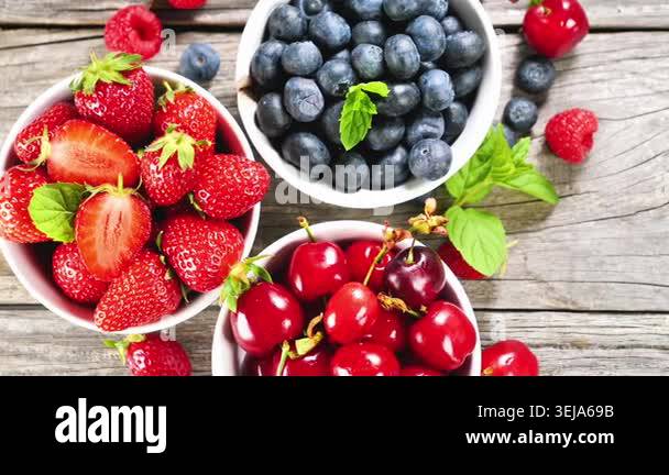 top view of fresh berries in bowls on rustic wooden table with copy ...