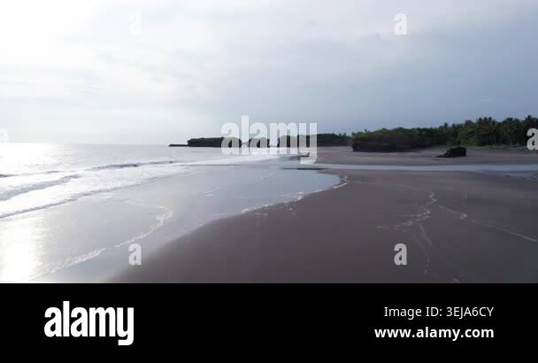 Drone captures Bali landscape with a beach, gentle waves, rocky ...