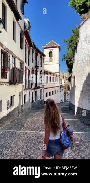 young woman walking down a historic cobblestone street in Albaicin ...