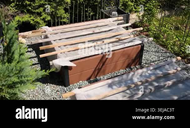 Panning shot of modern raised garden beds covered with white protective ...