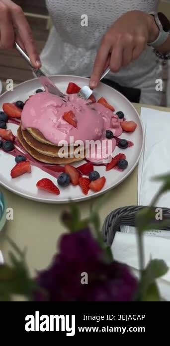 Woman Cutting Fluffy Pancakes with Pink Cream and Fresh Berries. Close ...