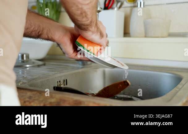 Man's hands diligently scrub a dirty plate with an orange and green ...