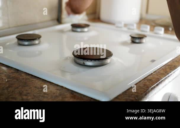 Close up shows a person actively cleaning the four gas burners and the ...