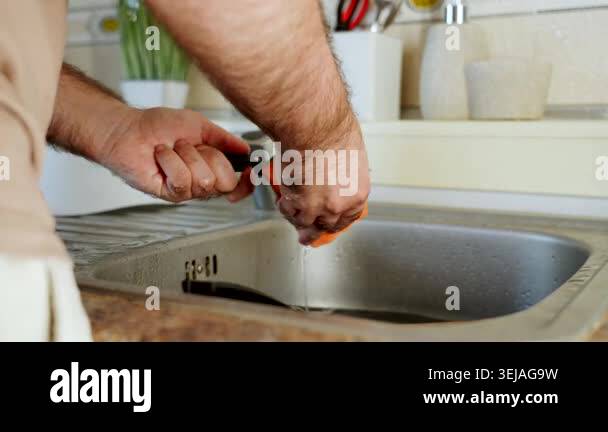 Person washes a kitchen knife sharpener in a stainless steel sink ...