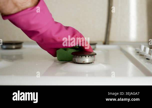 A person wearing a pink rubber glove uses a green sponge to thoroughly ...