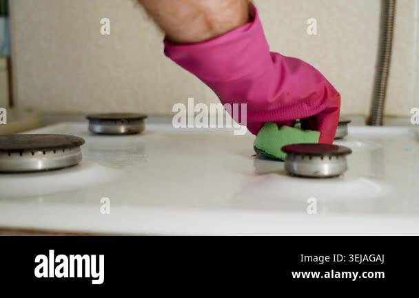 Hand in a vibrant pink glove vigorously scrubs accumulated grease and ...