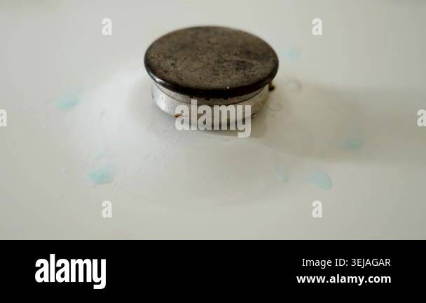A close up view of a dirty metal gas stove burner cap showing rust and ...