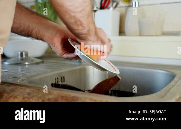 Close-up of a person's hands washing a plate with an orange and green ...