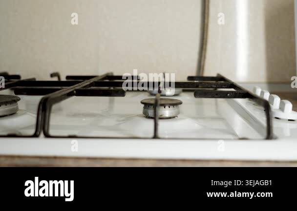 Close up of a clean white gas stovetop with metal grates and four ...