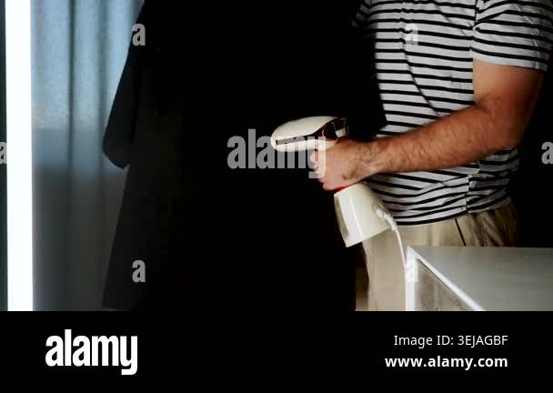 A man quickly removes wrinkles from a black t-shirt using a handheld ...