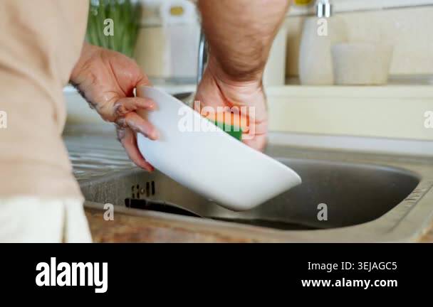 Hands thoroughly rinse a white ceramic bowl under running water in a ...