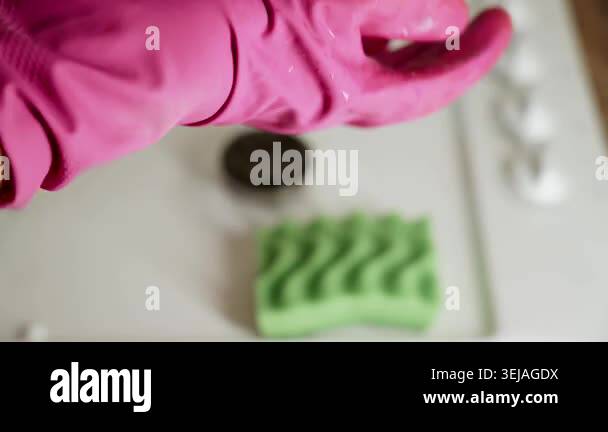 View of a hand in a bright pink cleaning glove reaching to scrub a ...