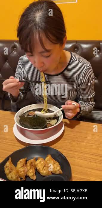 Young joyful Asian woman feeling relaxed eating hot ramen noodle soup ...
