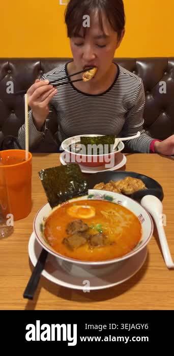 Happy Asian adult woman enjoying hot spicy ramen noodle soup using ...