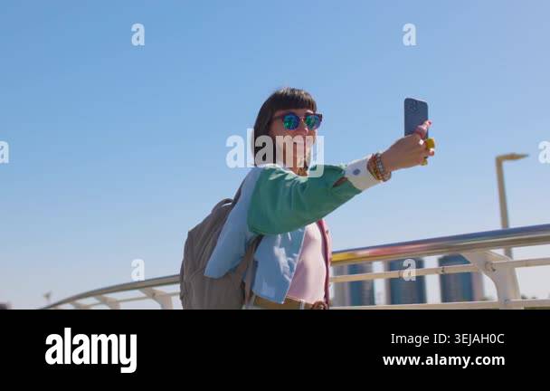 A young woman takes a photo of the Tel Aviv cityscape on her smartphone ...