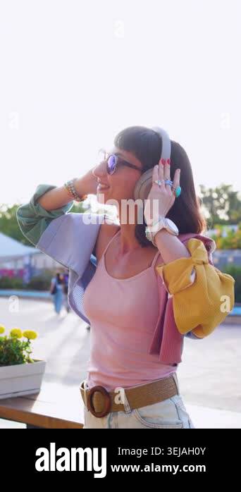 vertical shot. A slender, stylishly dressed woman smiles while ...