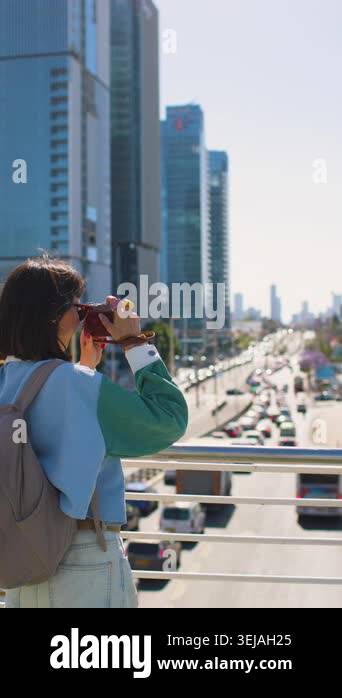 A young tourist photographs the Tel Aviv cityscape on a pedestrian ...