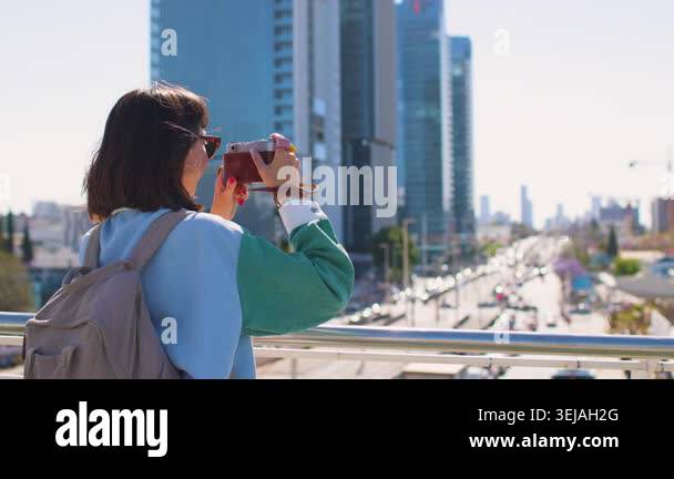 A young tourist photographs the Tel Aviv cityscape on a pedestrian ...