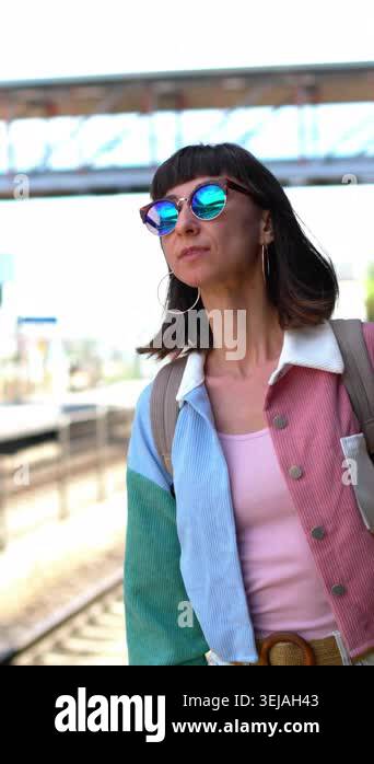 vertical video. Portrait of a happy young woman at a train station. A ...