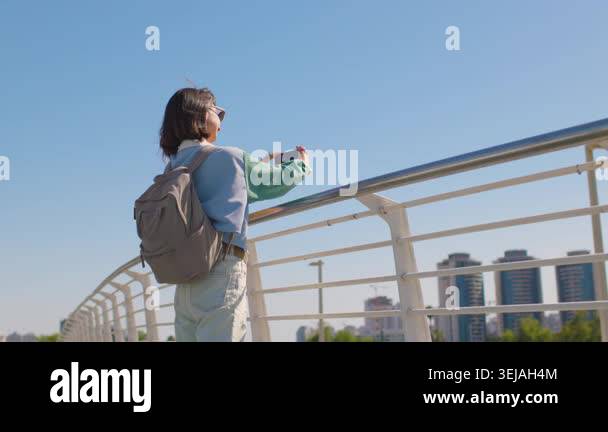 A young woman takes a photo of the Tel Aviv cityscape on her smartphone ...