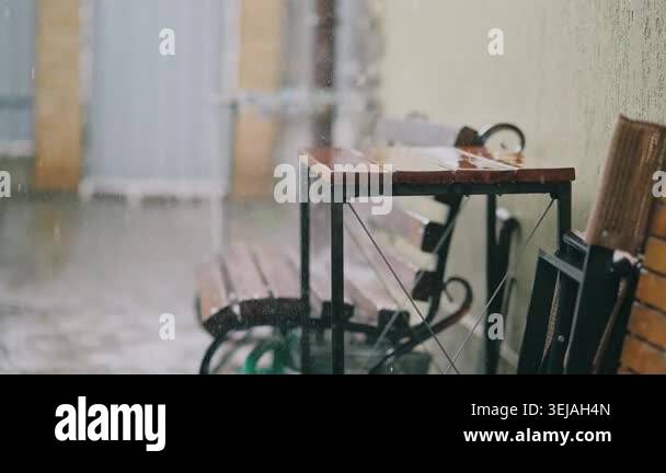 Heavy rain pouring outdoors with water drops splashing on wooden table ...