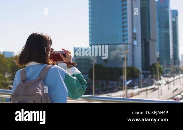 A tourist takes a photo of a cityscape. The tourist with the camera is ...