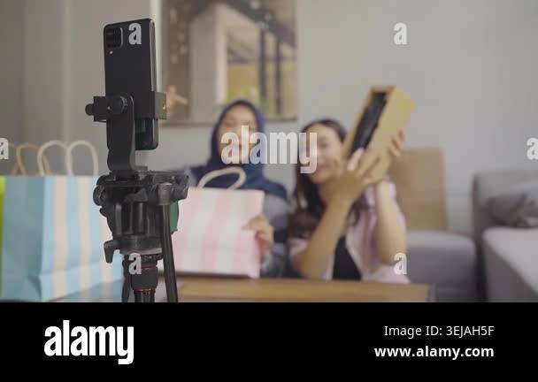 Two women unboxing shopping haul on couch recording with smartphone on ...