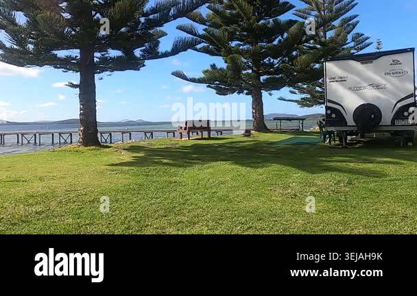 A recreational vehicle is parked near a serene waterfront, surrounded ...